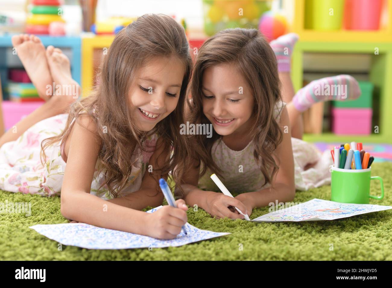 Two cute little girls drawing with pencils Stock Photo - Alamy