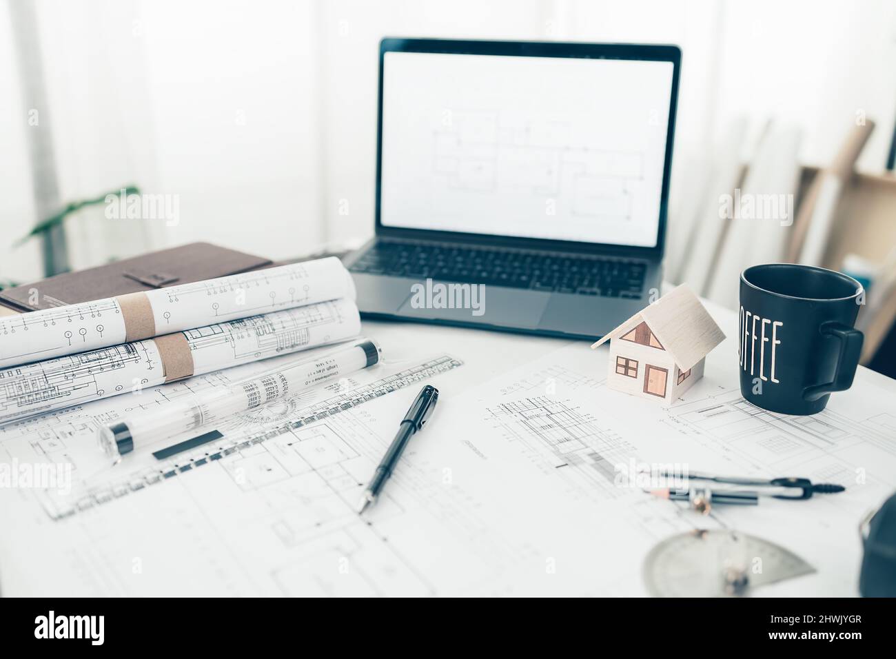 Mini model house, pencil, protractor, tape measure, compass, laptop and ...