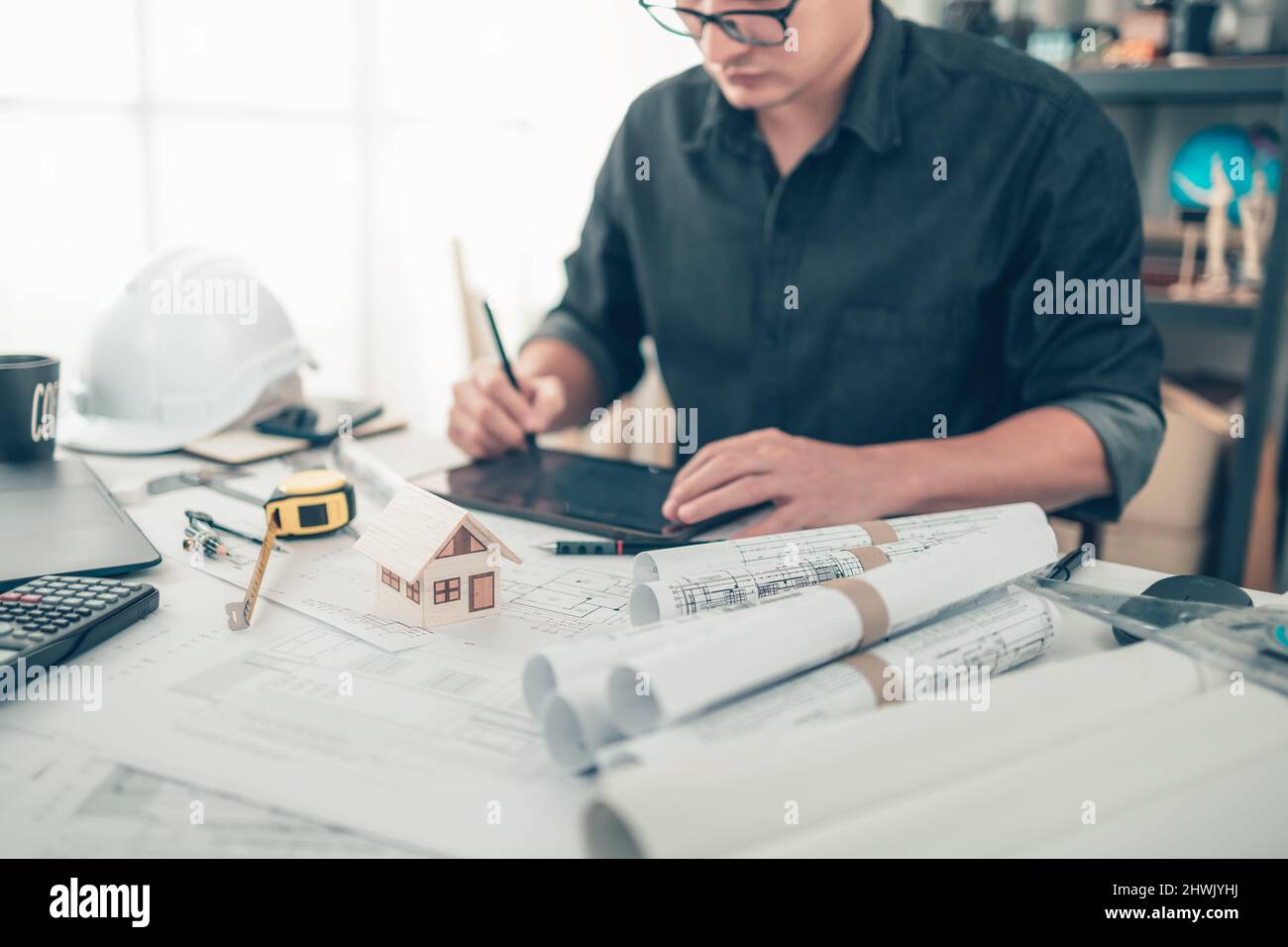 Mini model house on blueprint plan while architector working on tablet ...