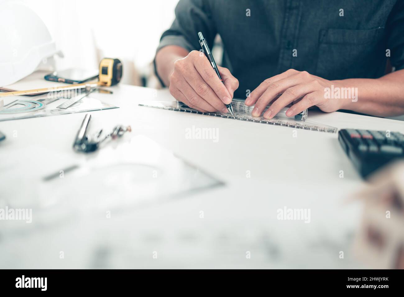 Architect engineer use pen and mini T-slide drawing design working on bueprint. House planning ...