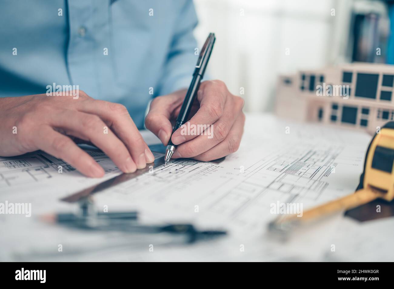 Architect engineer use pen and angle protector drawing design working on bueprint. House ...