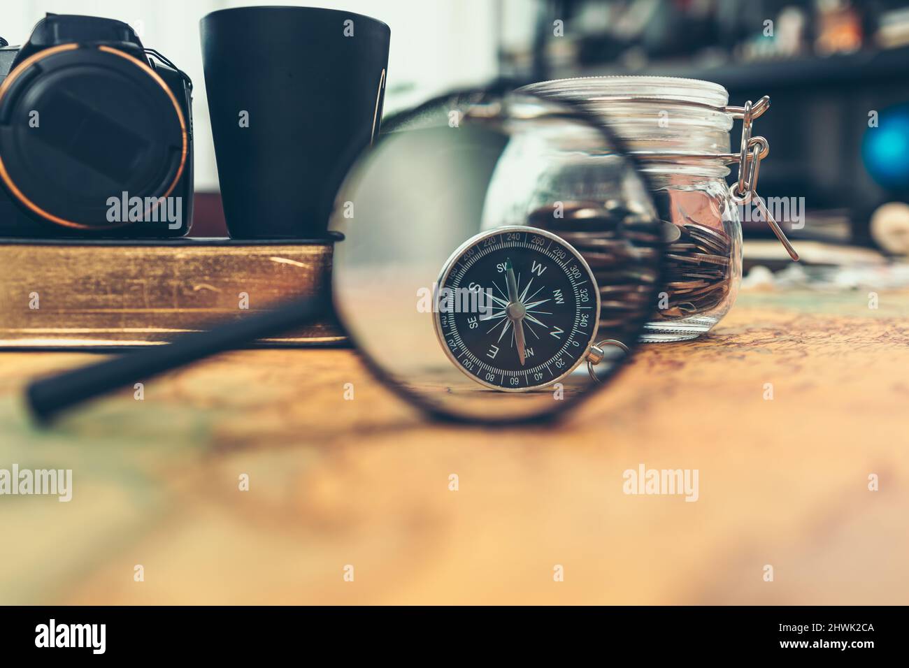 Compass look through a magnifying glass and money in glass jar on world ...