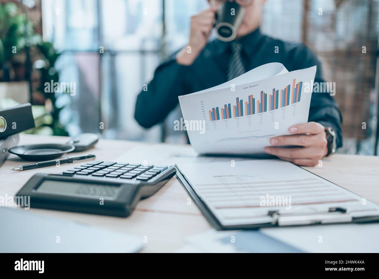Accountant drinking coffee and working on calculator to calculate ...