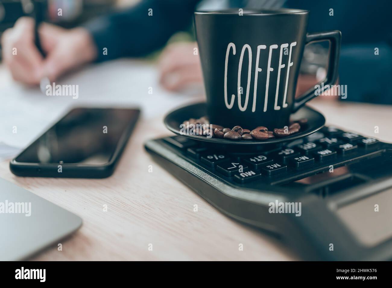 Cup of coffee on calculator and Accountant working on calculator to ...