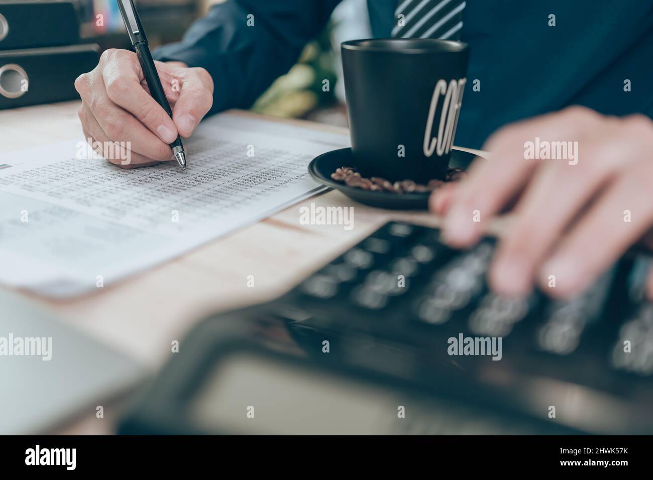 Accountant writing and checking while working on calculator to ...