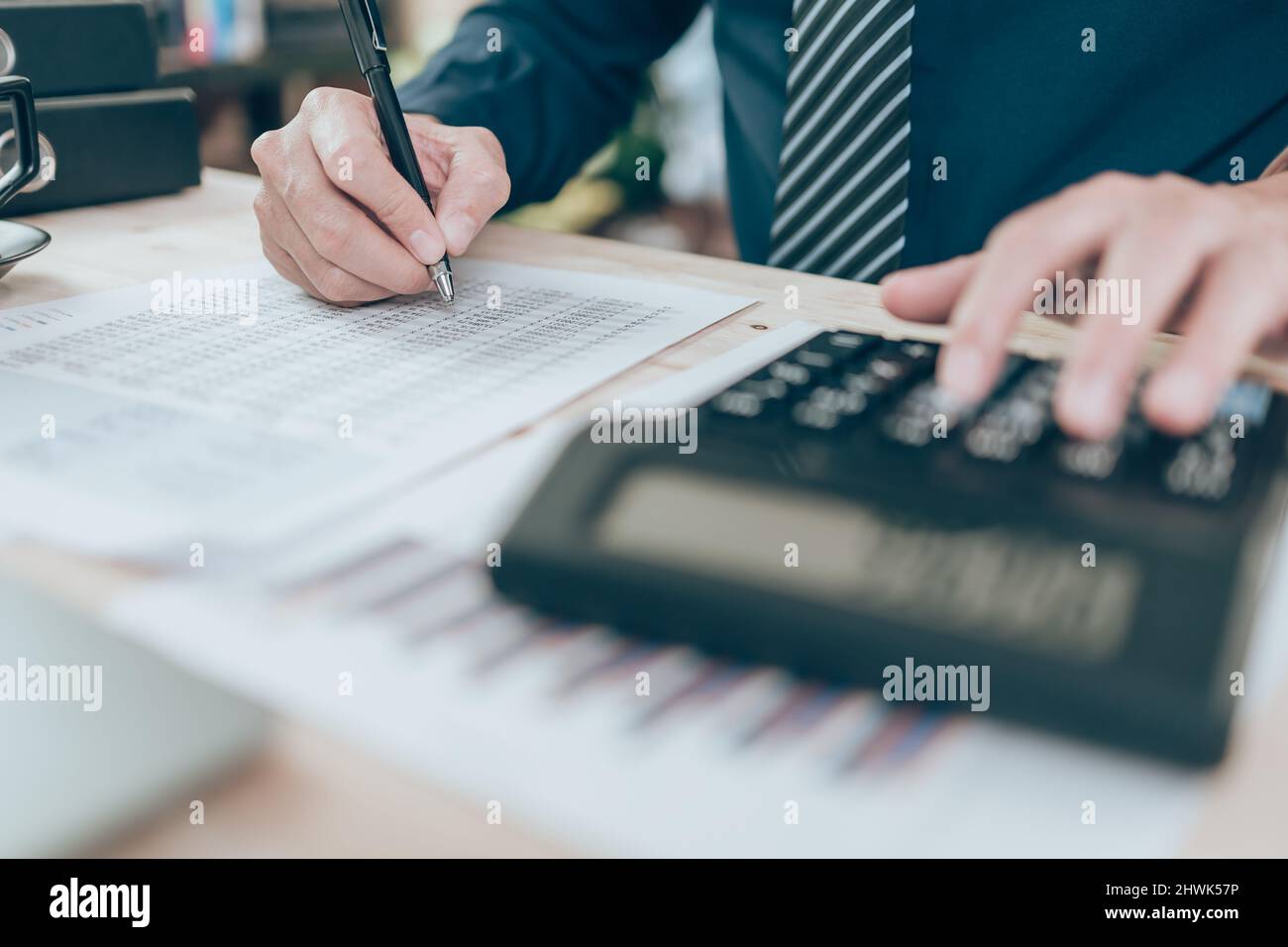 Accountant writing and checking while working on calculator to ...