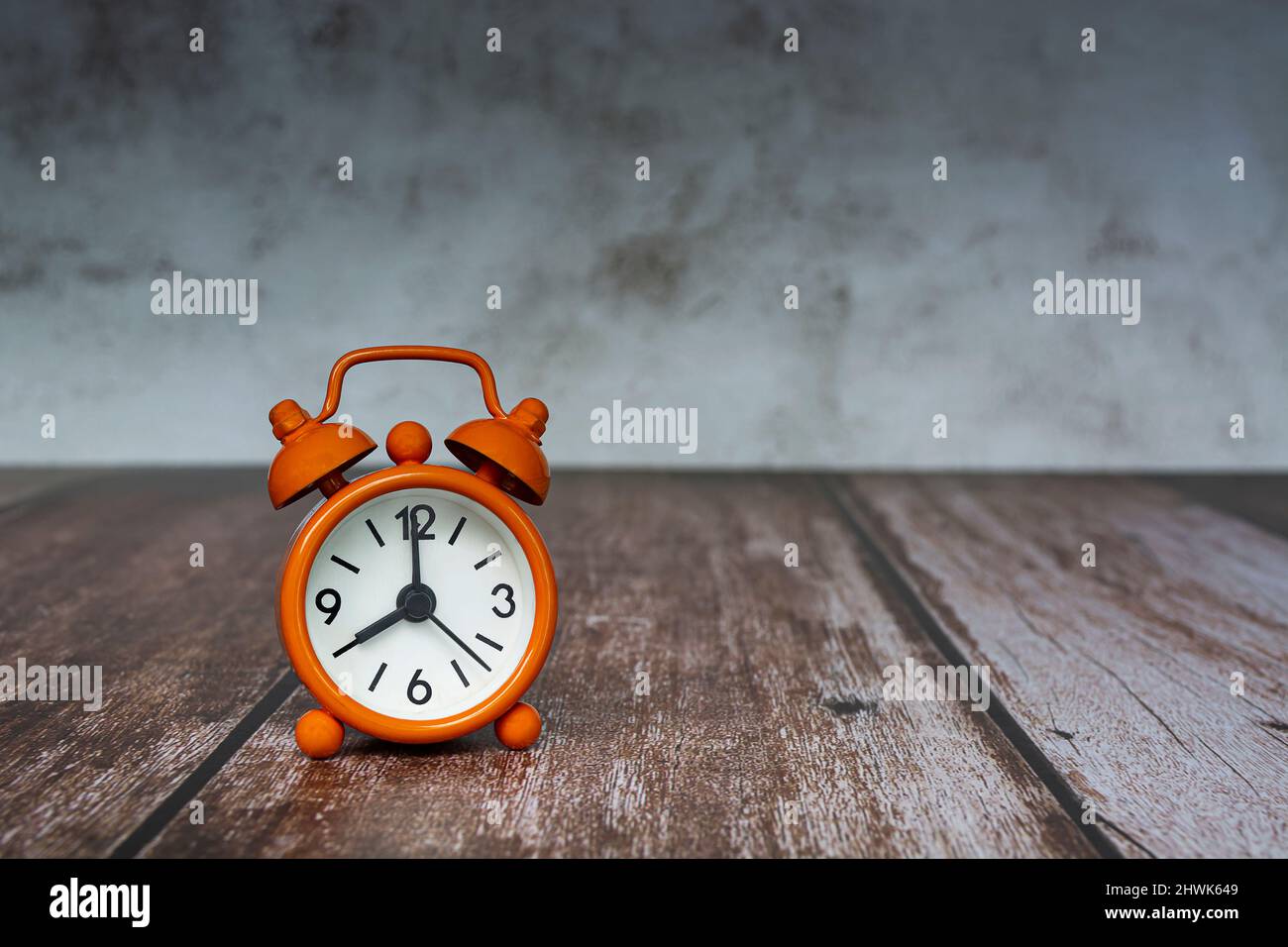 Orange alarm clock isolated on wooden desk. The clock set at 8 o'clock ...