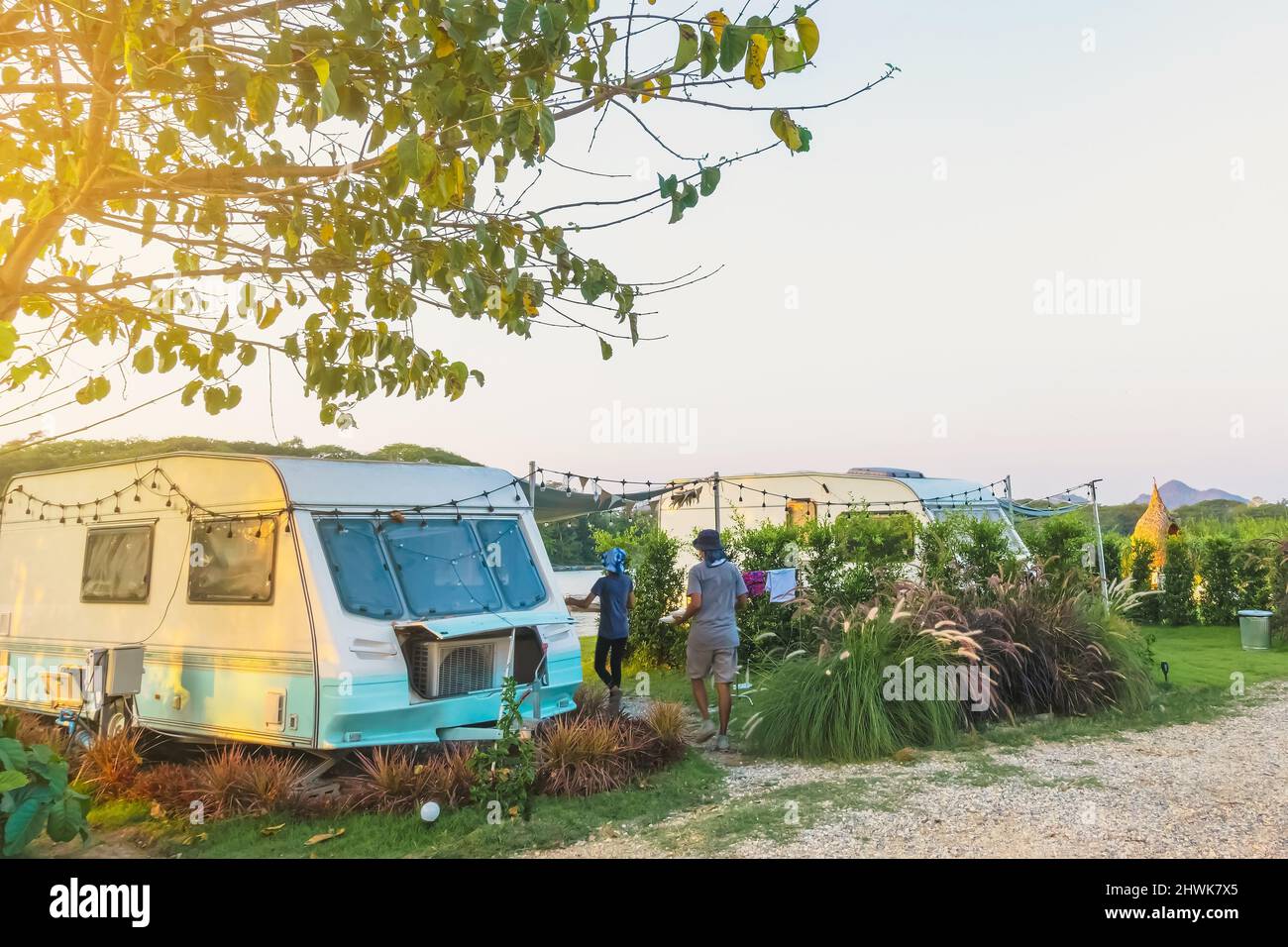 Cozy retro travel trailer Caravan on green grass before sunset near ...
