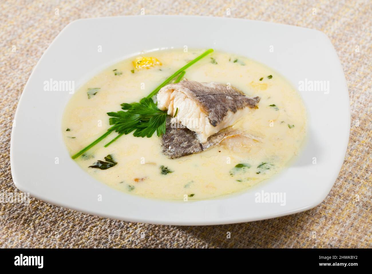 Creamy soup with white fish hake served with greens at plate Stock ...