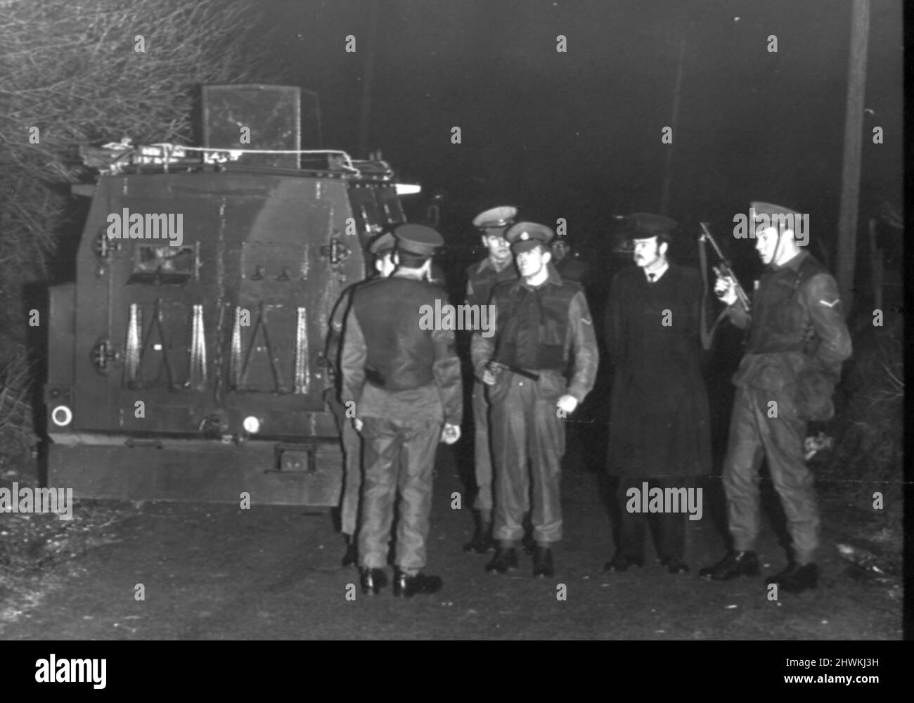 Beside an armoured car, troops & police at the spot where three ...