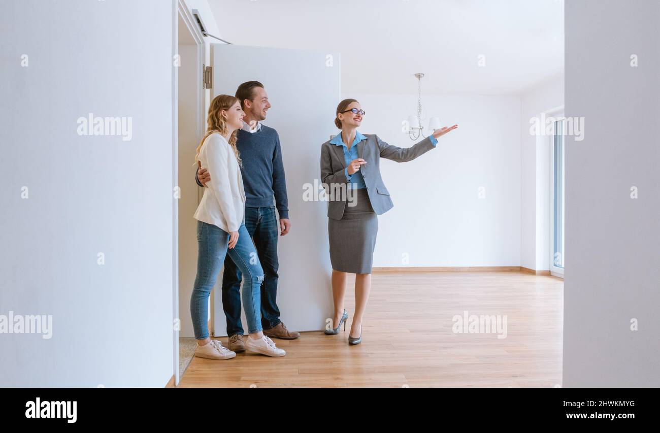 Realtor showing house to a young couple Stock Photo - Alamy