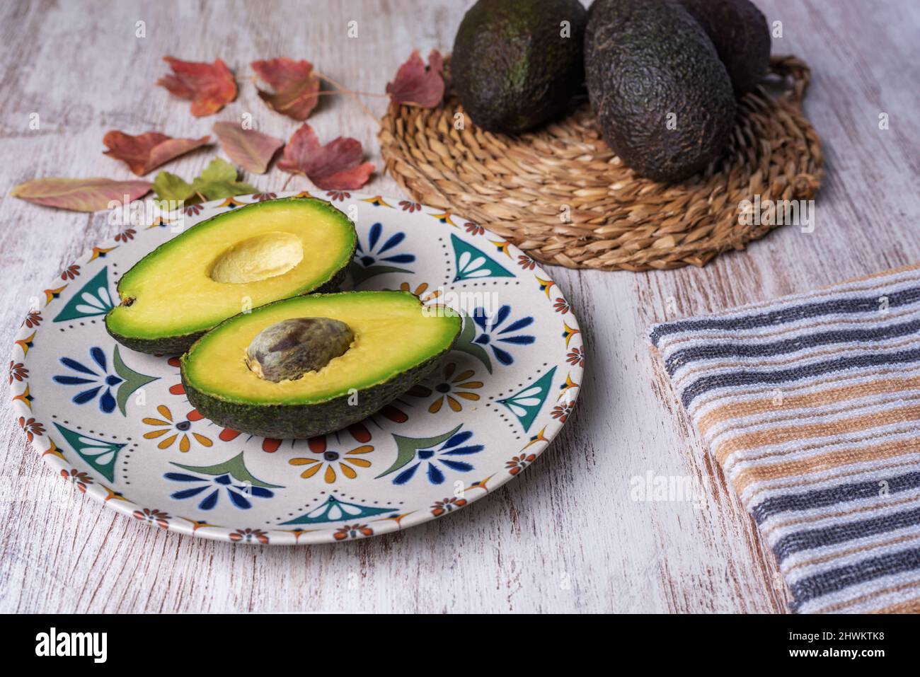 Plate with an avocado cut into two pieces next to other avocados Stock ...