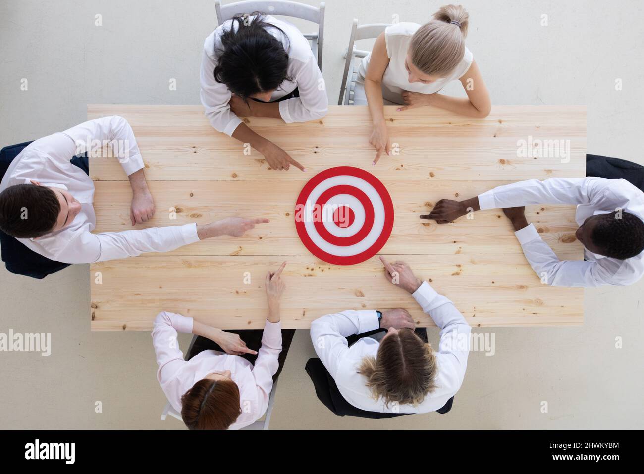 Team of business people pointing at red target at meeting table Stock ...