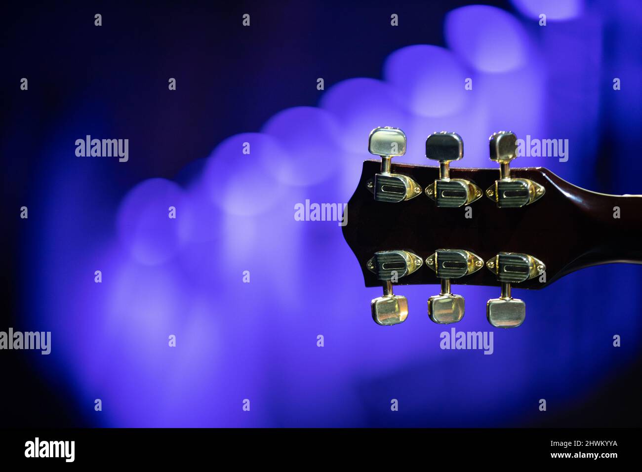 The headstock and neck of an electric guitar against the lights during ...