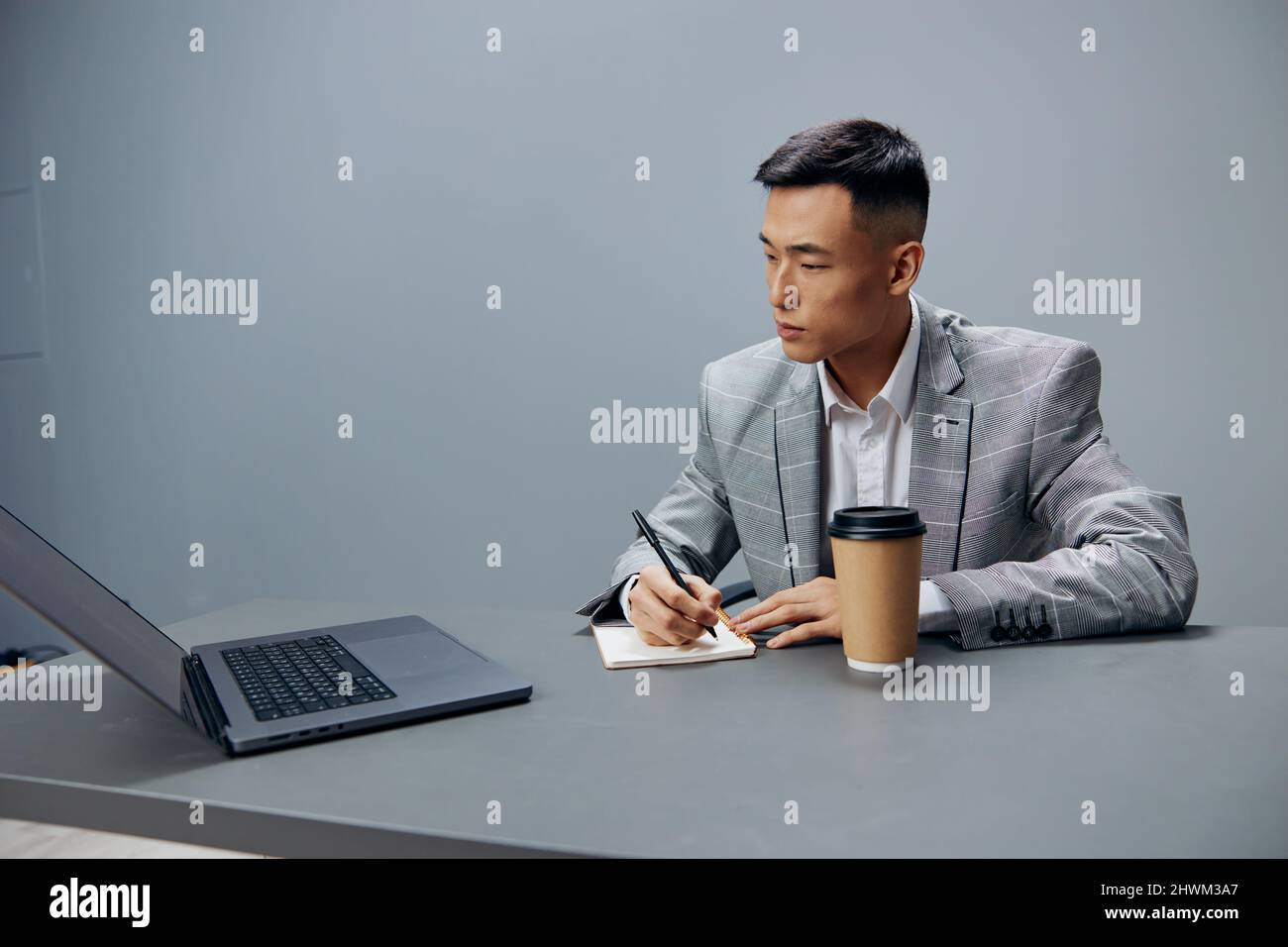 Asian man writing in a notebook laptop work at the desktop Lifestyle ...