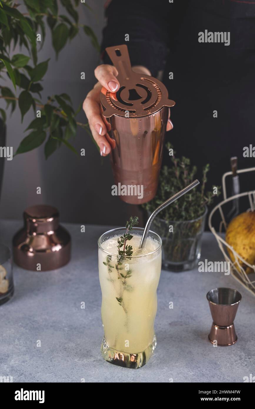 Real woman preparing Pear Collins Cocktail in highball glass on light ...