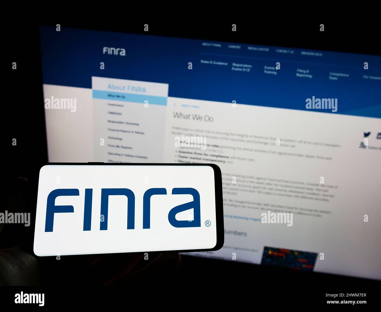 Person holding mobile phone with logo of Financial Industry Regulatory ...