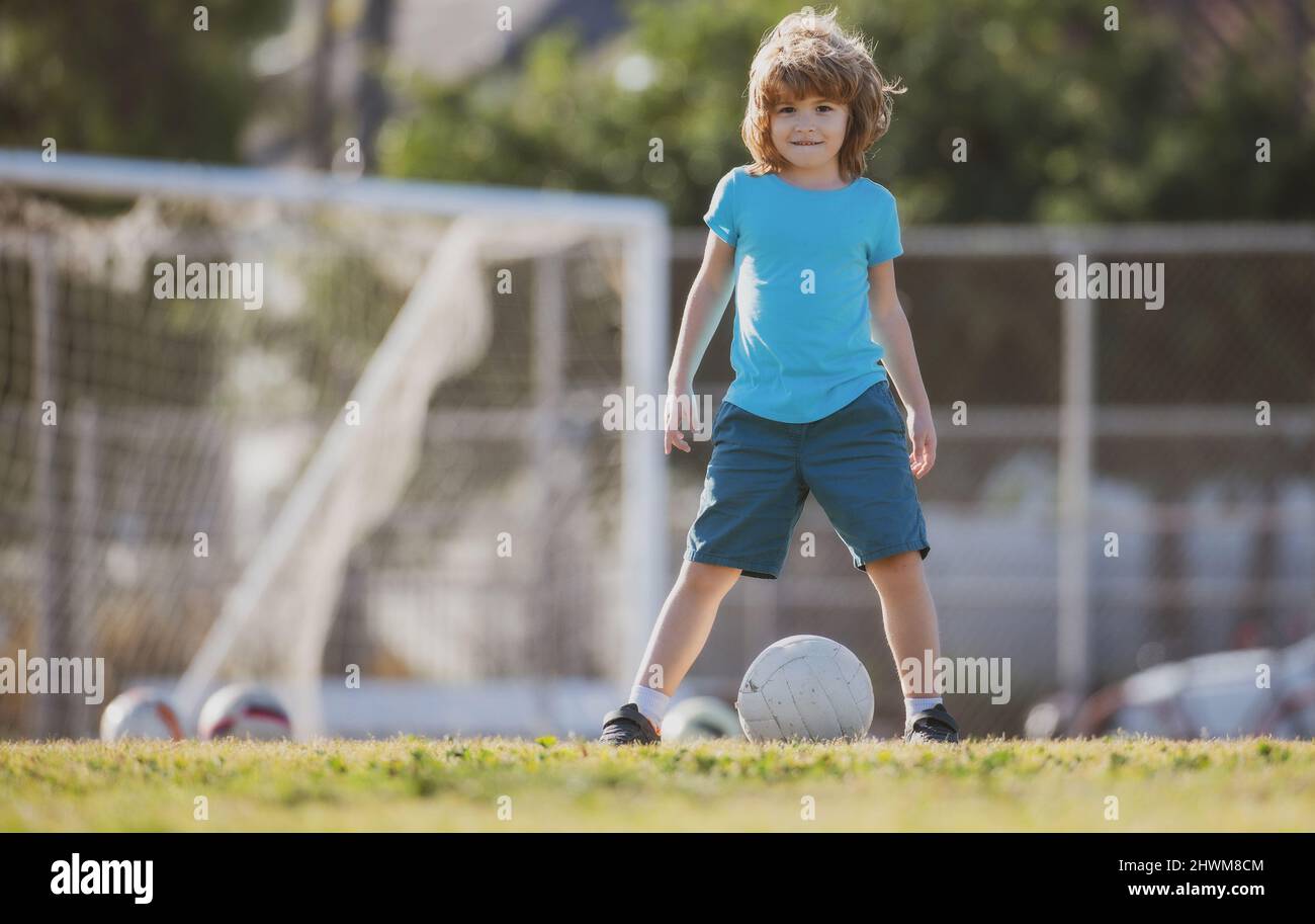 Excited child boy kicking ball in the grass outdoors. Soccer kids ...