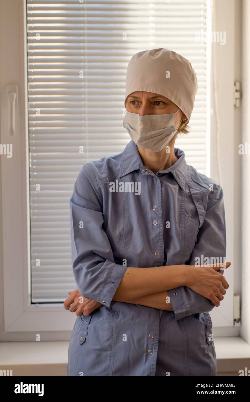 A female doctor stands in the hospital wearing a blue uniform and a ...