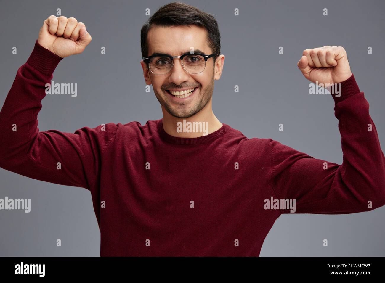 successful man wearing glasses holds hands above head posing gesture ...