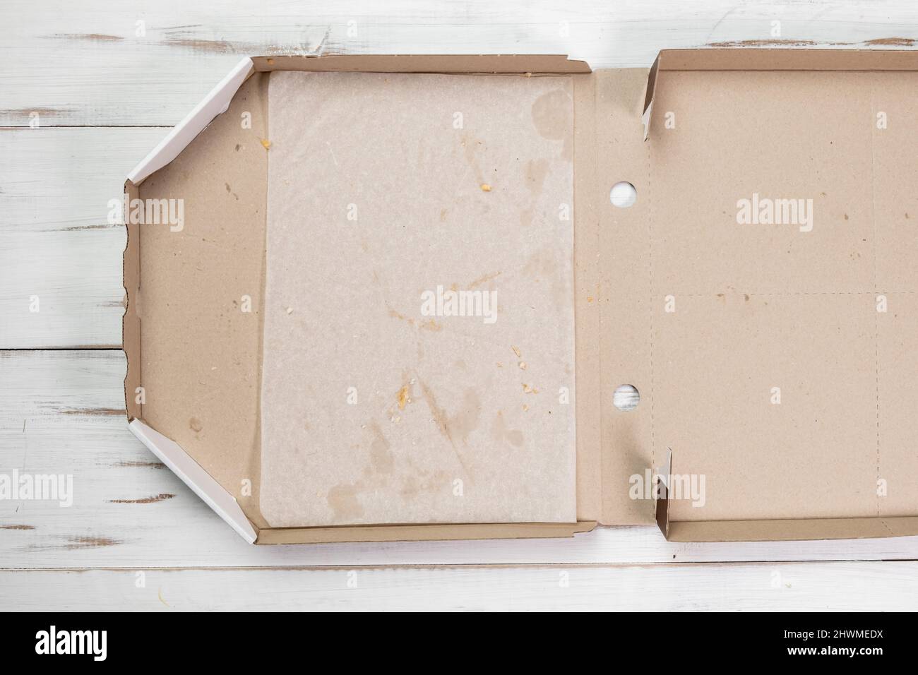 Empty open pizza box. White wooden background. Eaten pizza. Top view ...