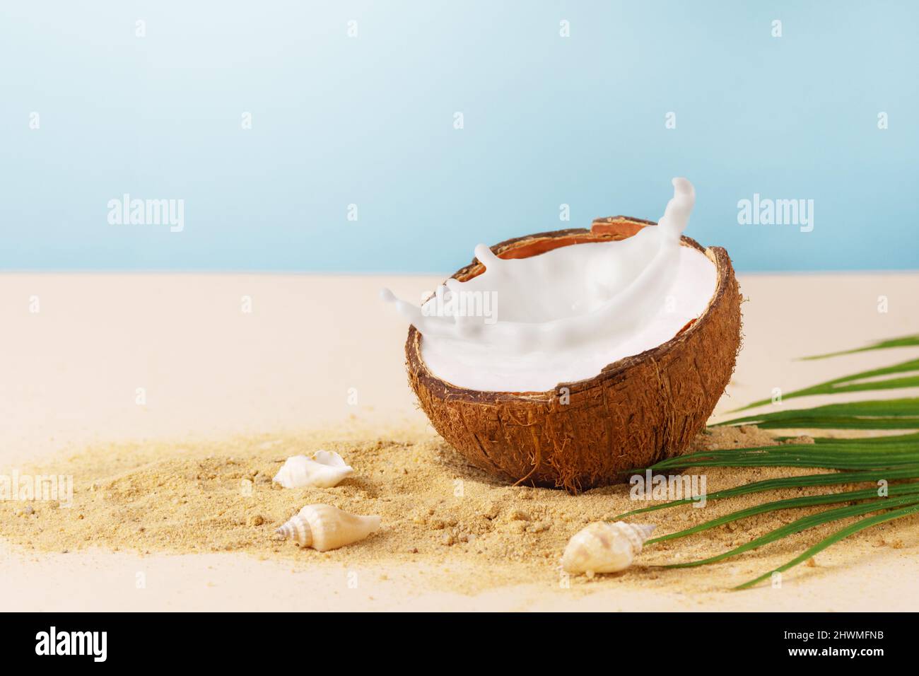 Halved coconut with milk splash on summer background with beach sand ...