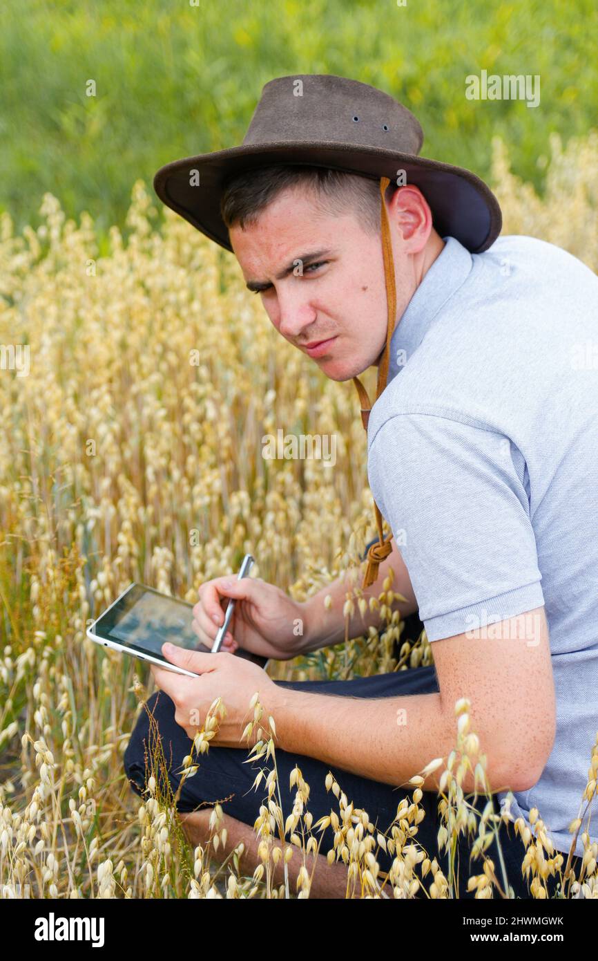 Digital farm. Portrait of farmer seating in gold wheat field and ...