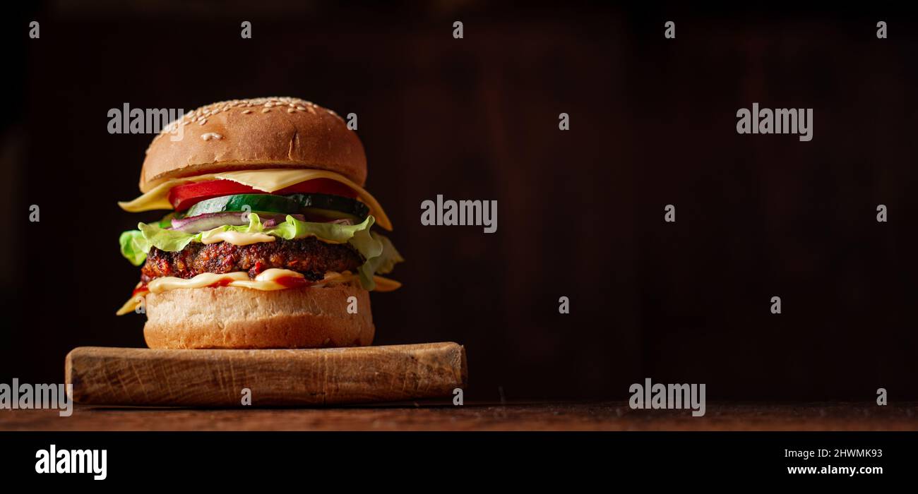 Hamburger on a dark wooden background. Banner. Place for text ...
