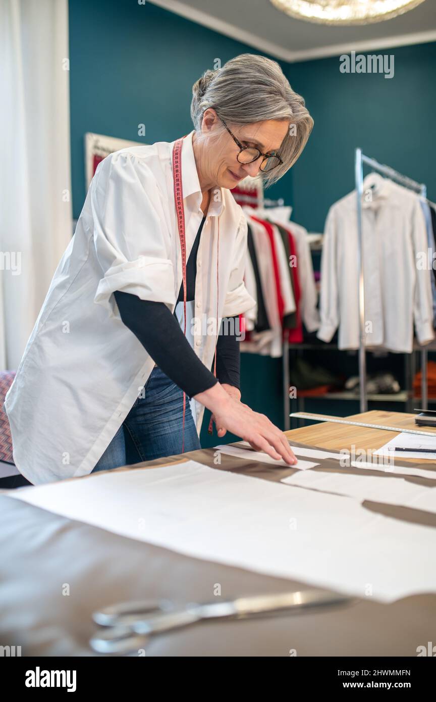 Woman laying out paper pattern on fabric Stock Photo - Alamy