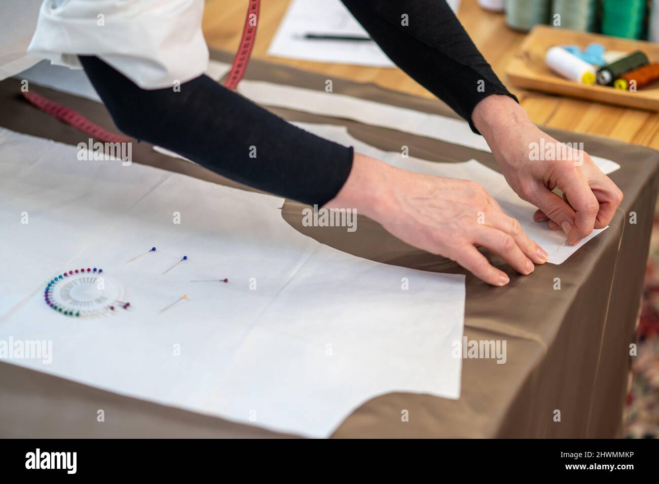 Womens hands with pin touching pattern on fabric Stock Photo - Alamy