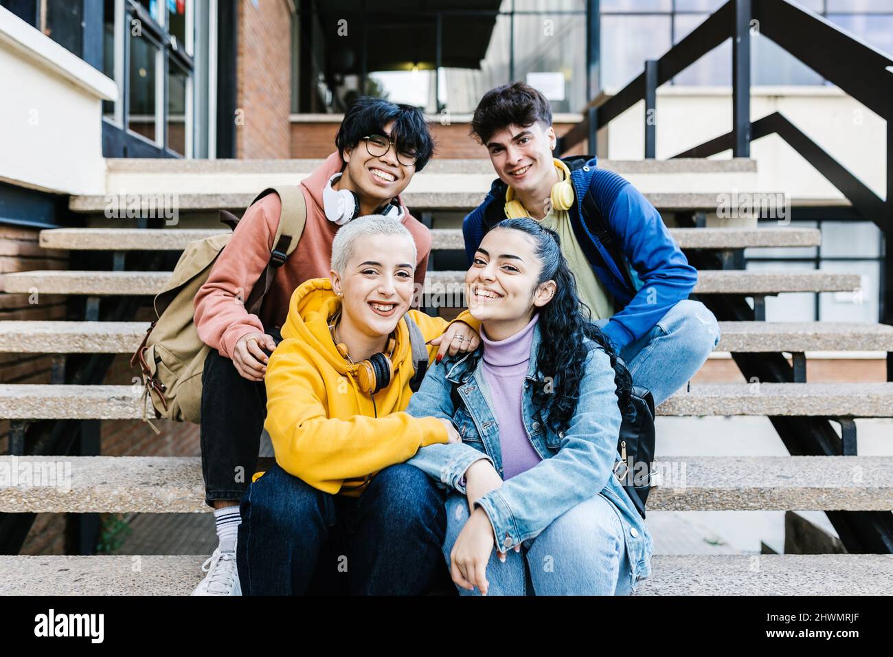 Millennial group of young students friends sitting on college campus ...