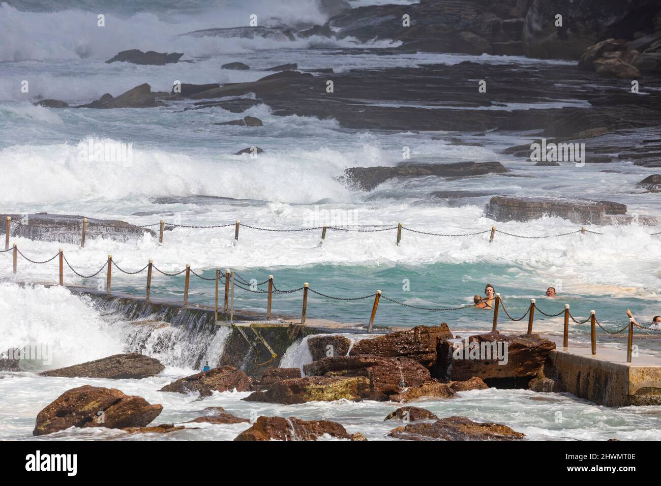 Avalon Beach Rockpool with wild ocean surf and people swimming in the ...