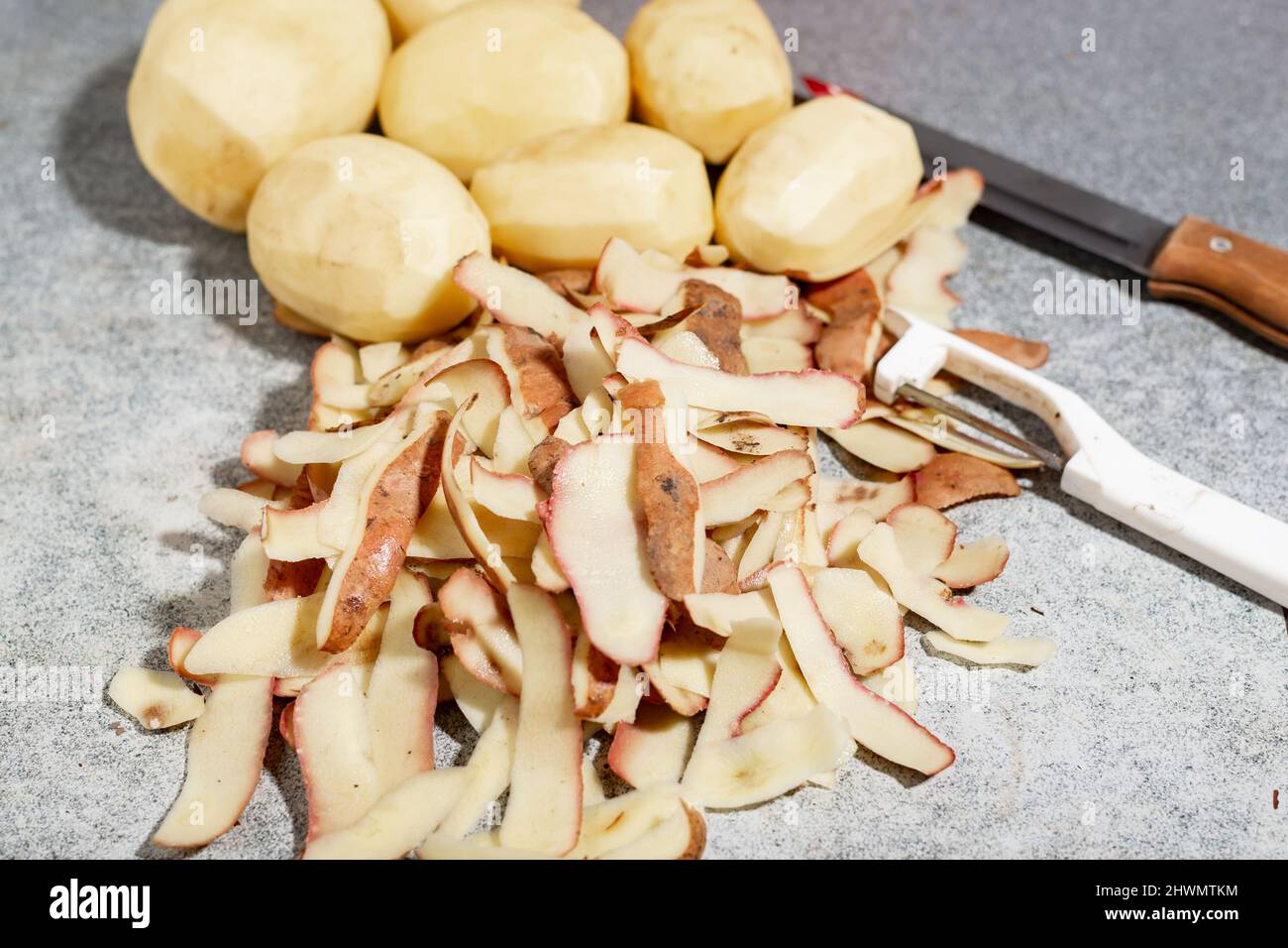 Peeled raw potato tubers and potato skins. Preparation for cooking ...