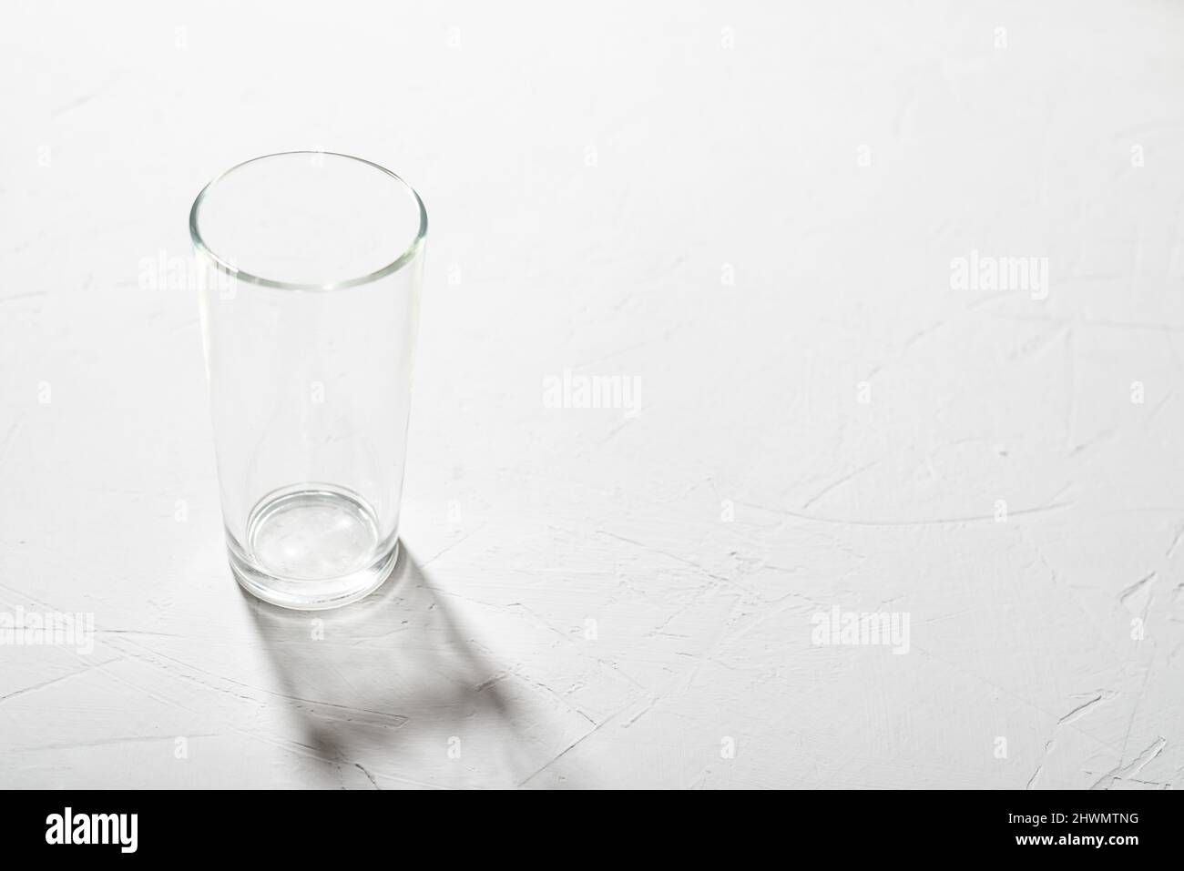 Empty glass beaker on a white background. Clear shadow, hard light ...