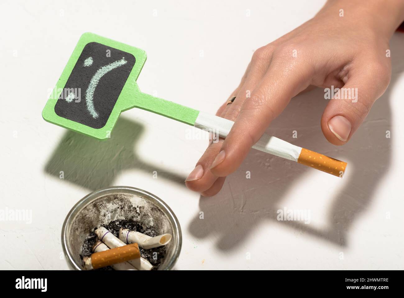 Harm of smoking concept. Unhappy smiley and in a cigarette in a woman's ...