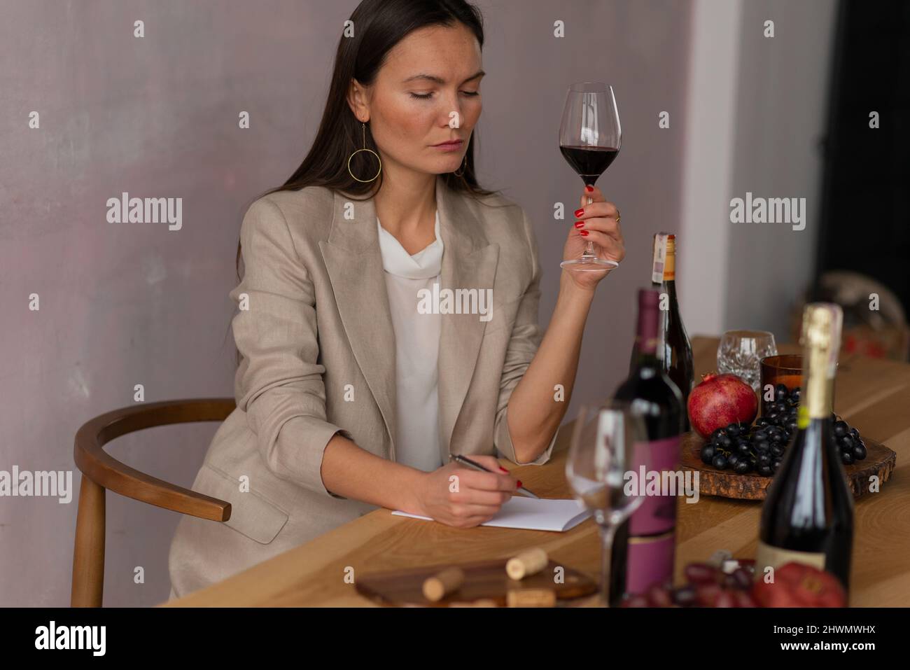 Sommelier woman writing notes testing wine in glass Stock Photo - Alamy