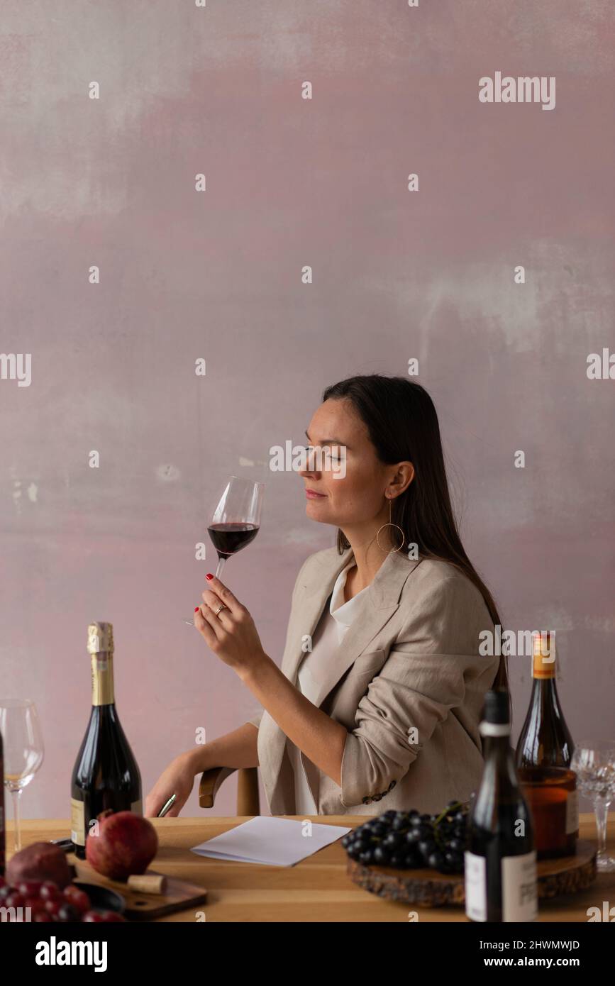 Beautiful female sommelier on degustation of wine on pink background ...