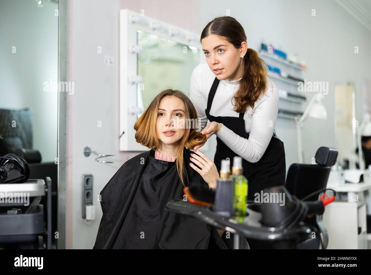 Young woman professional hair stylist choosing hairdo for female client ...