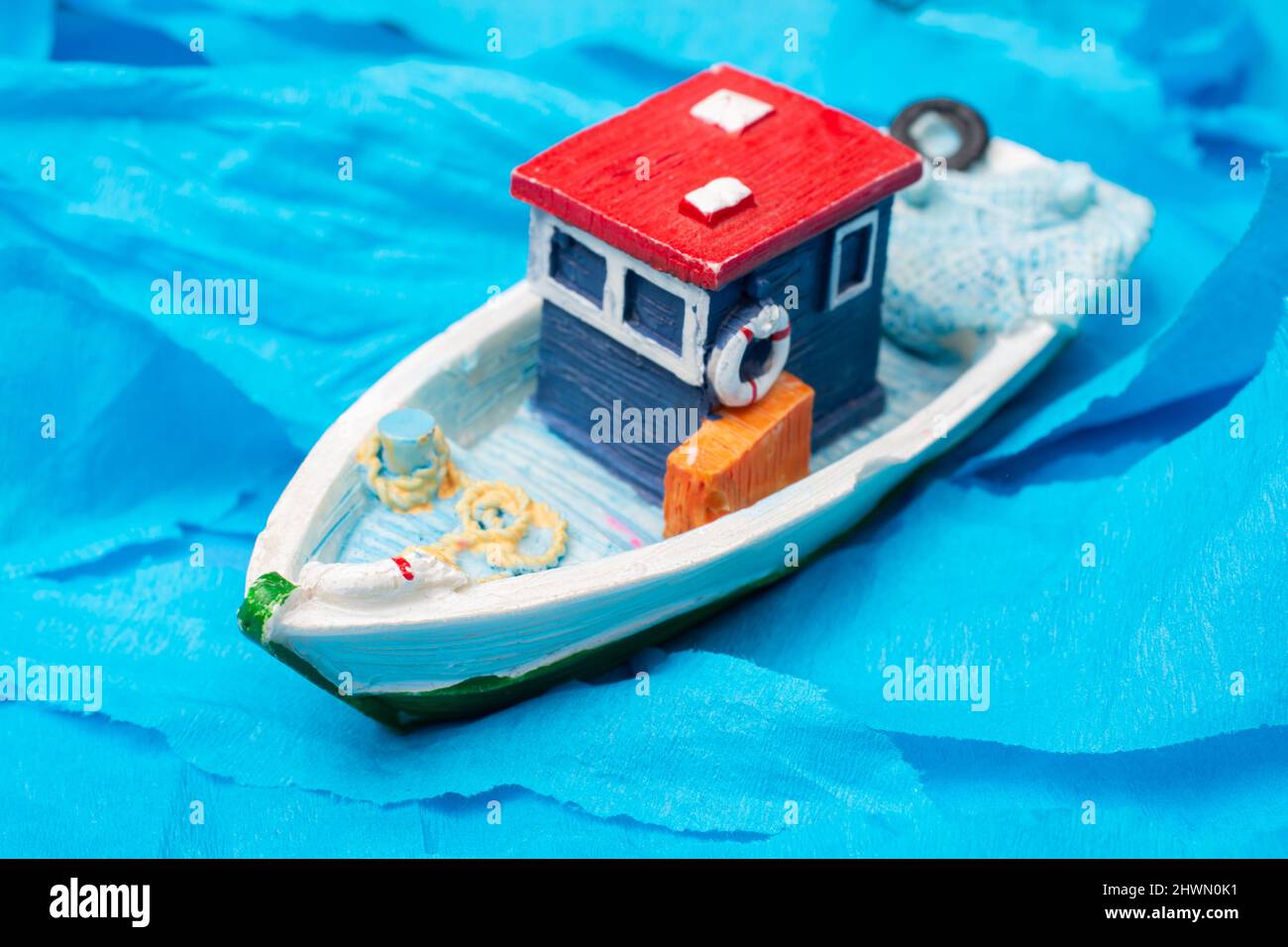 Little colorful model fishing boat placed on bloe paper Stock Photo - Alamy