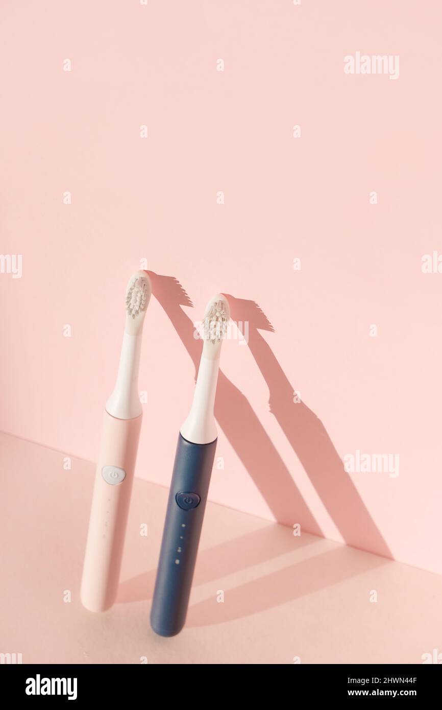 Two new modern ultrasonic toothbrushes. Dental care supplies on pink ...