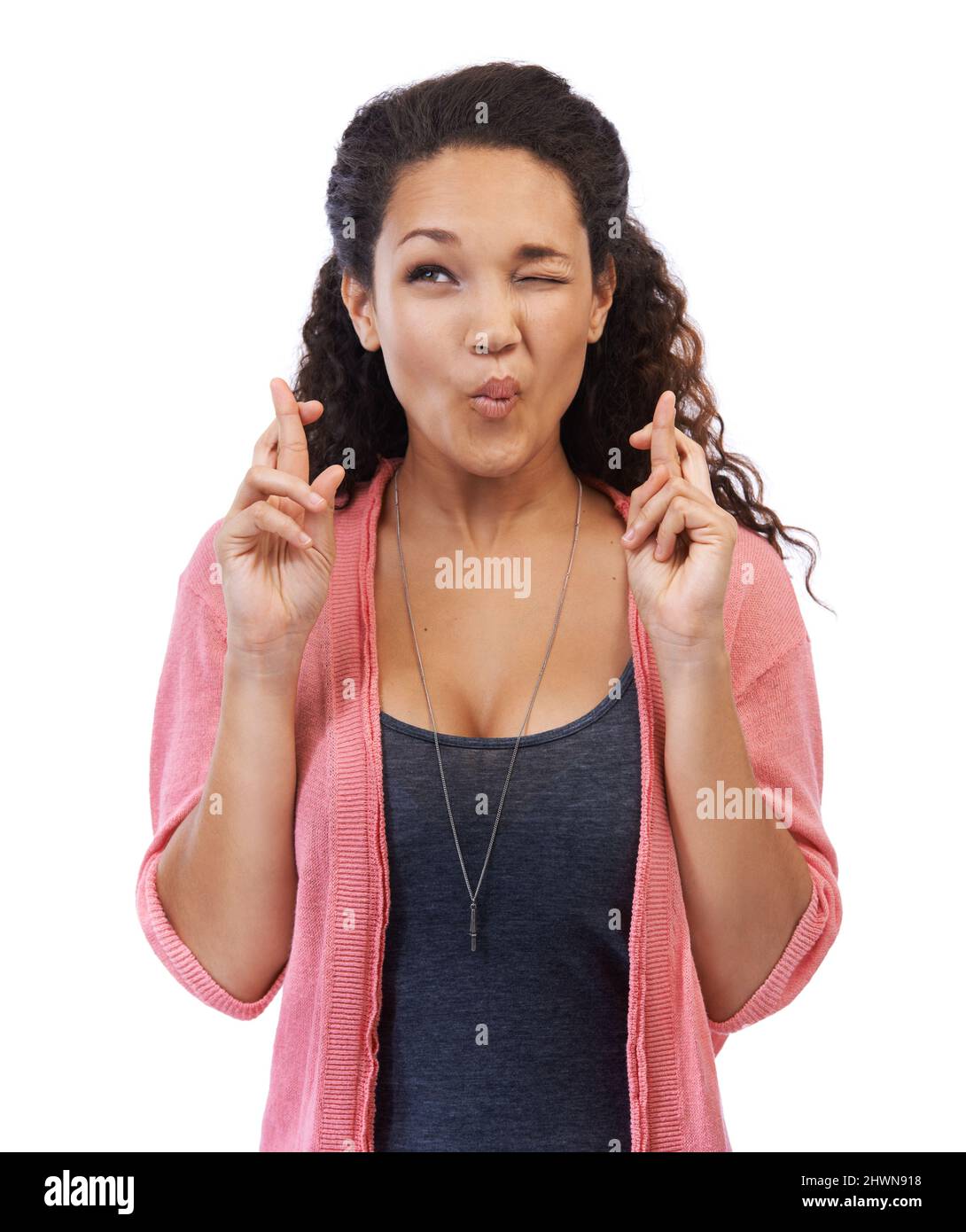 Fingers crossed. A beautiful young woman winking with fingers crossed ...