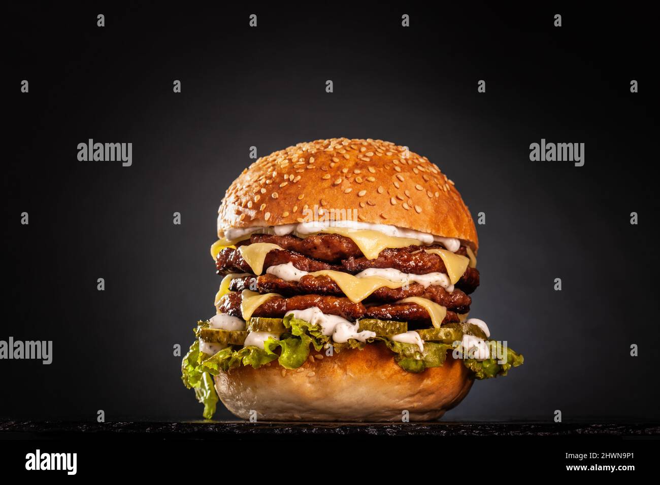 Quadruple burger with cheese cucumber and lettuce. Isolated on black ...