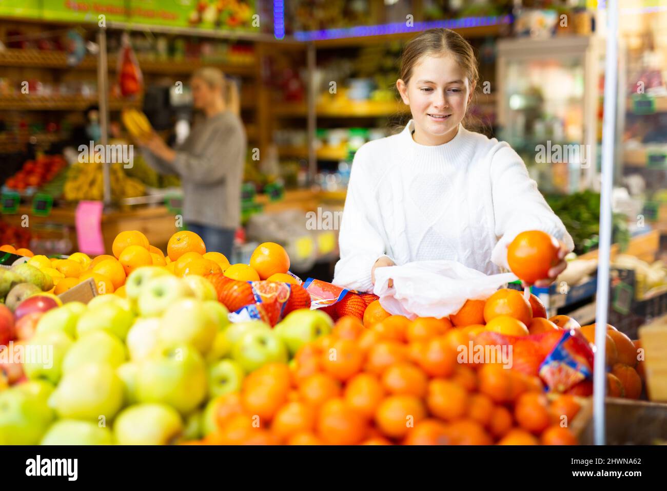 Cheerful teen girl choosing sweet oranges in local food store Stock ...