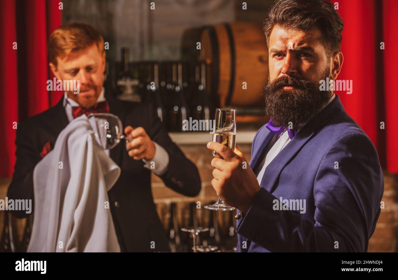 Barman at counter. Man holds glass of champagne. Confident bearded man ...