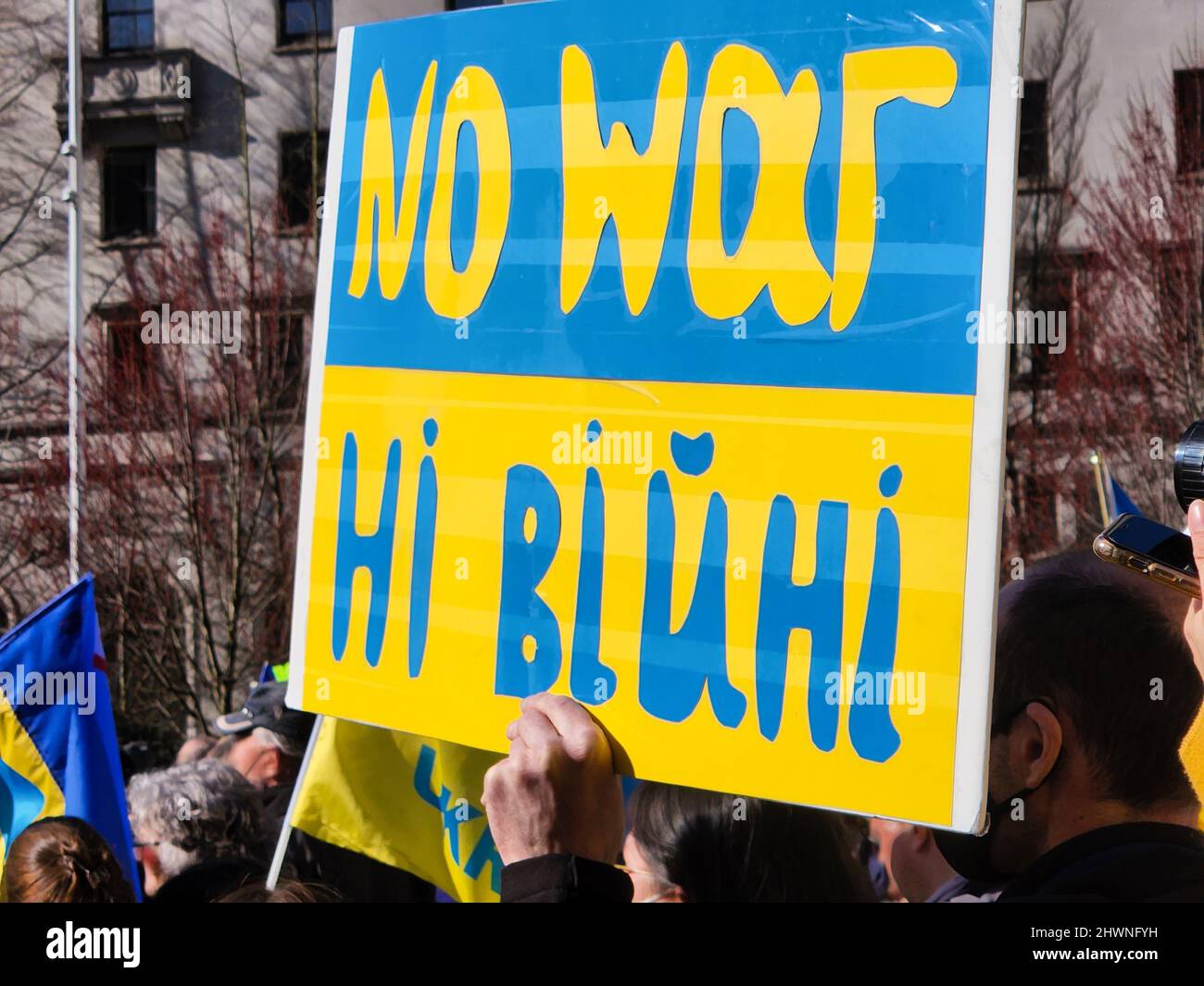 A man at a rally holds in his hand a poster calling for no war Stock ...