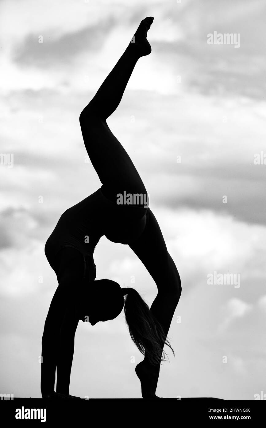 Girl gymnastic silhouette on sky. Young slender girl doing acrobatic ...