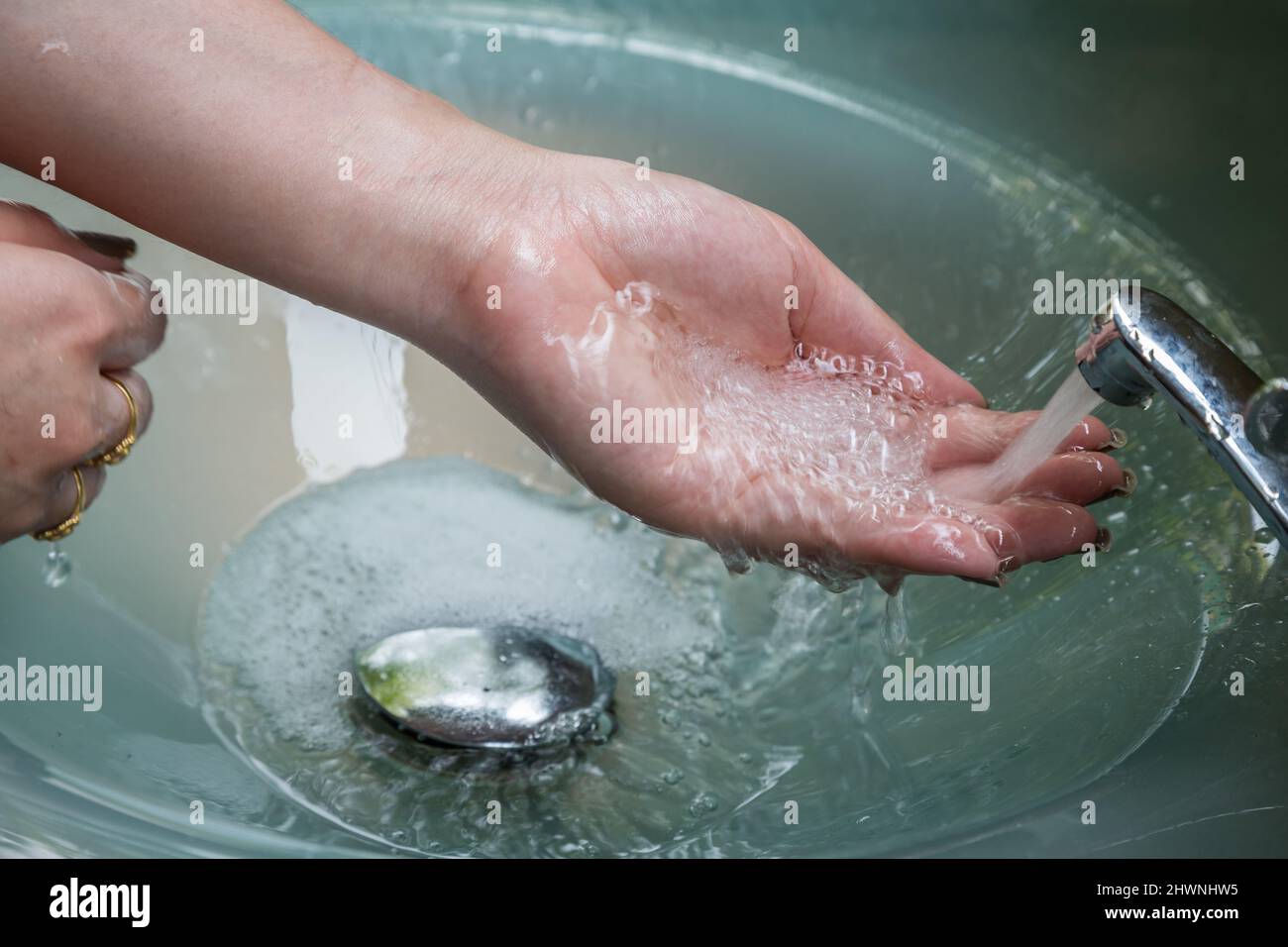 Washing hands under flowing tap water flow on sink Stock Photo - Alamy