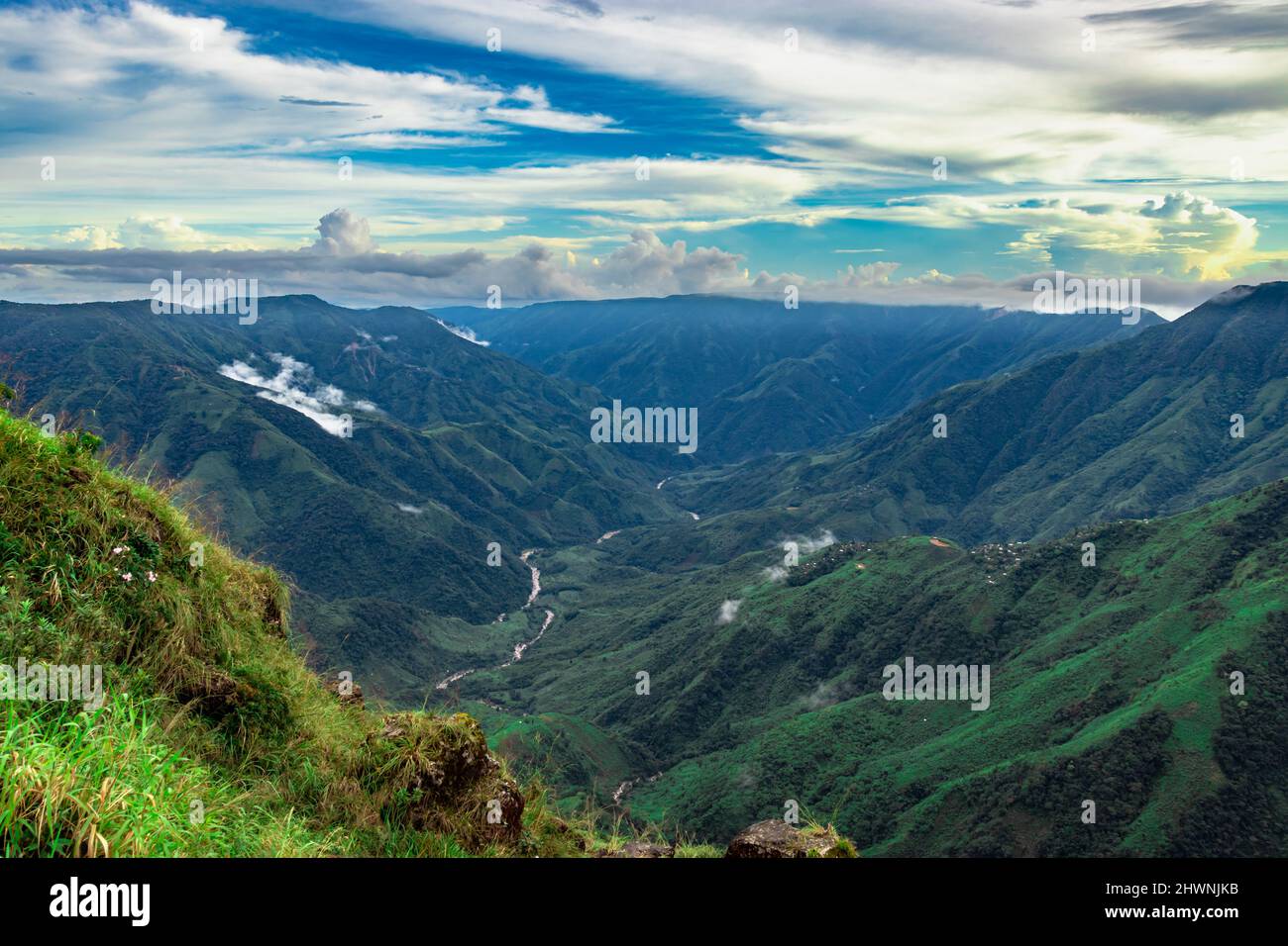 mountain valley covered with green forests and bright blue sky at ...