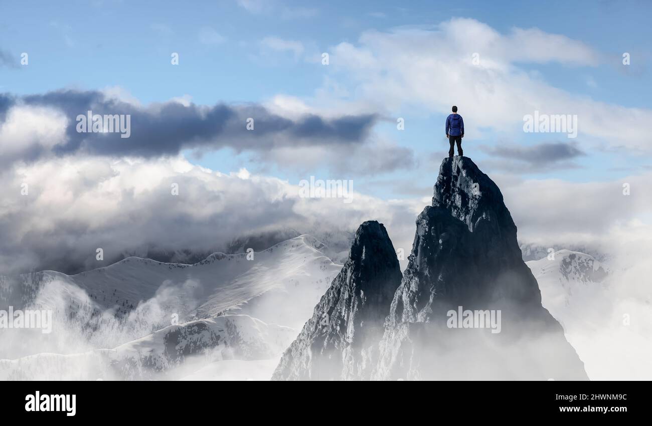 Adventurous Man Hiker standing on top of icy peak with rocky mountains ...