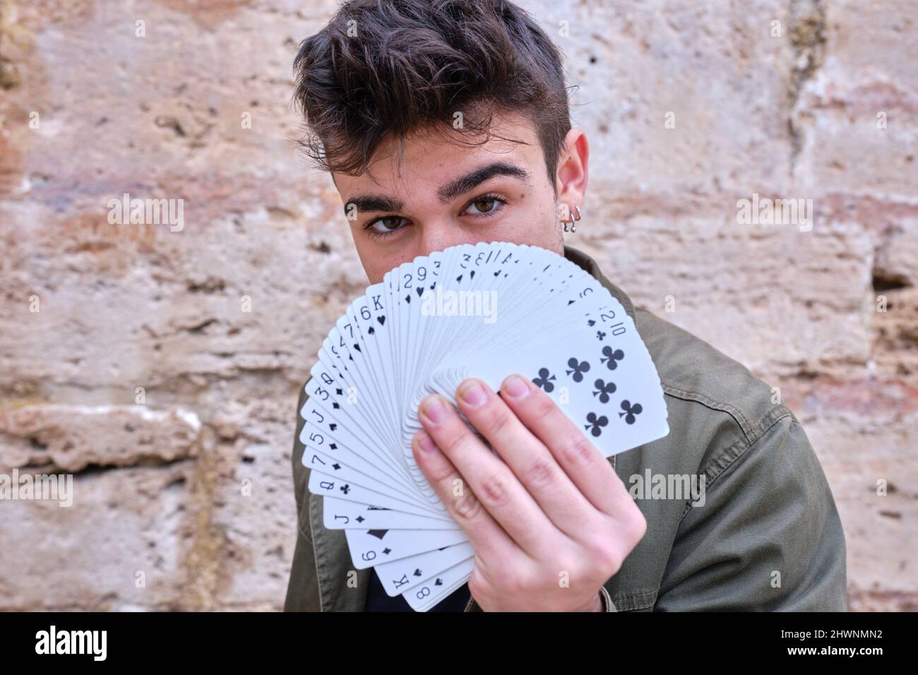 Street magician hiding behind a pack of cards in his hand Stock Photo ...
